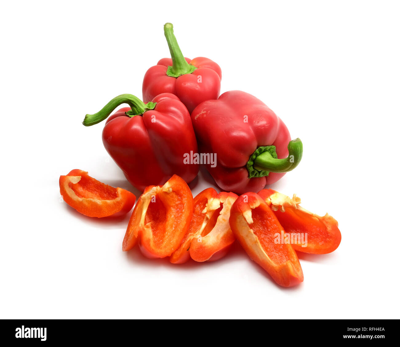 Still life with three whole and sliced red ripe bell peppers isolated ...