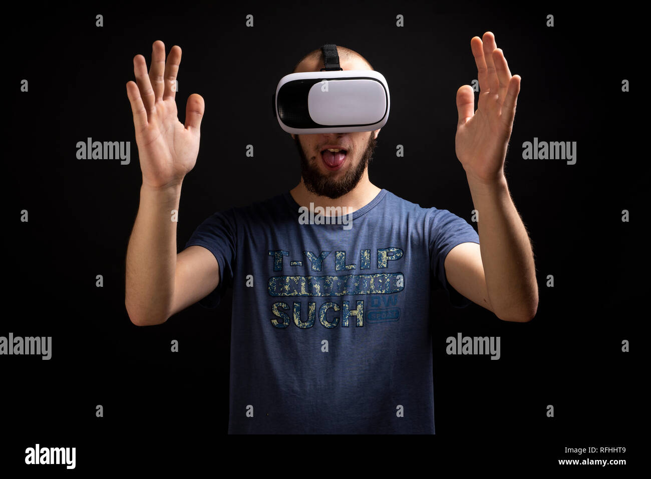 Male using VR headset raising both hands and displaying tongue. Indoors ...