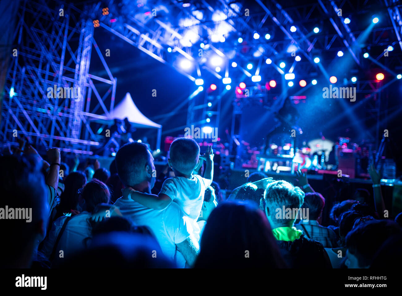 Young boy and his family attending a concert and rising hands in the ...
