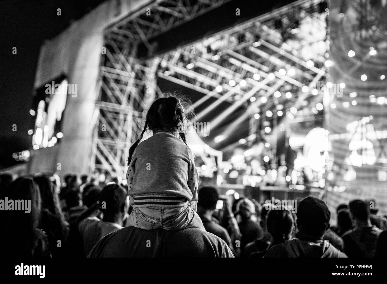 Young girl watching a concert from her dad shoulders, black and white ...