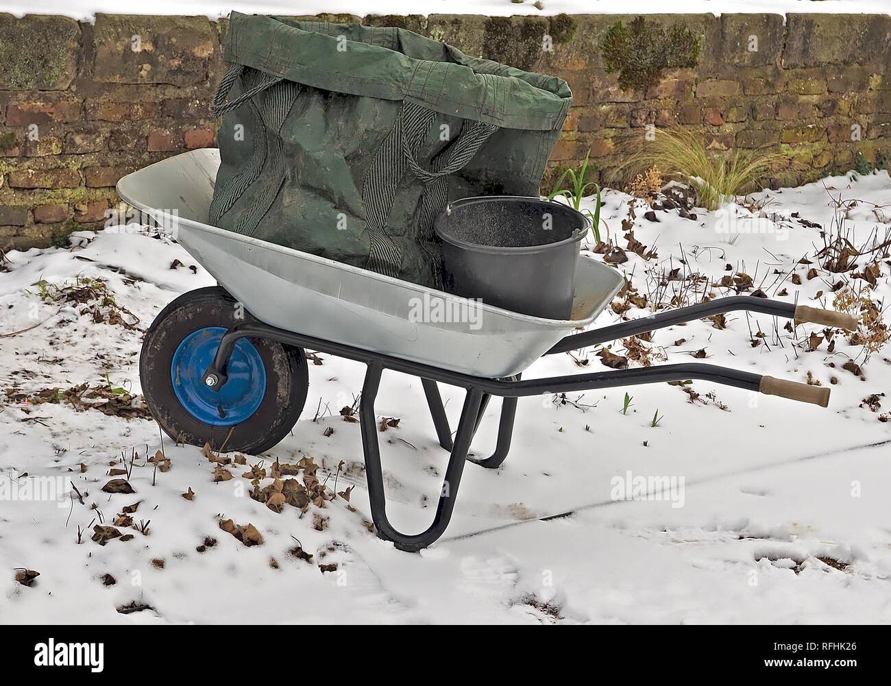 Wheelbarrow with gardening items in the snow Stock Photo - Alamy