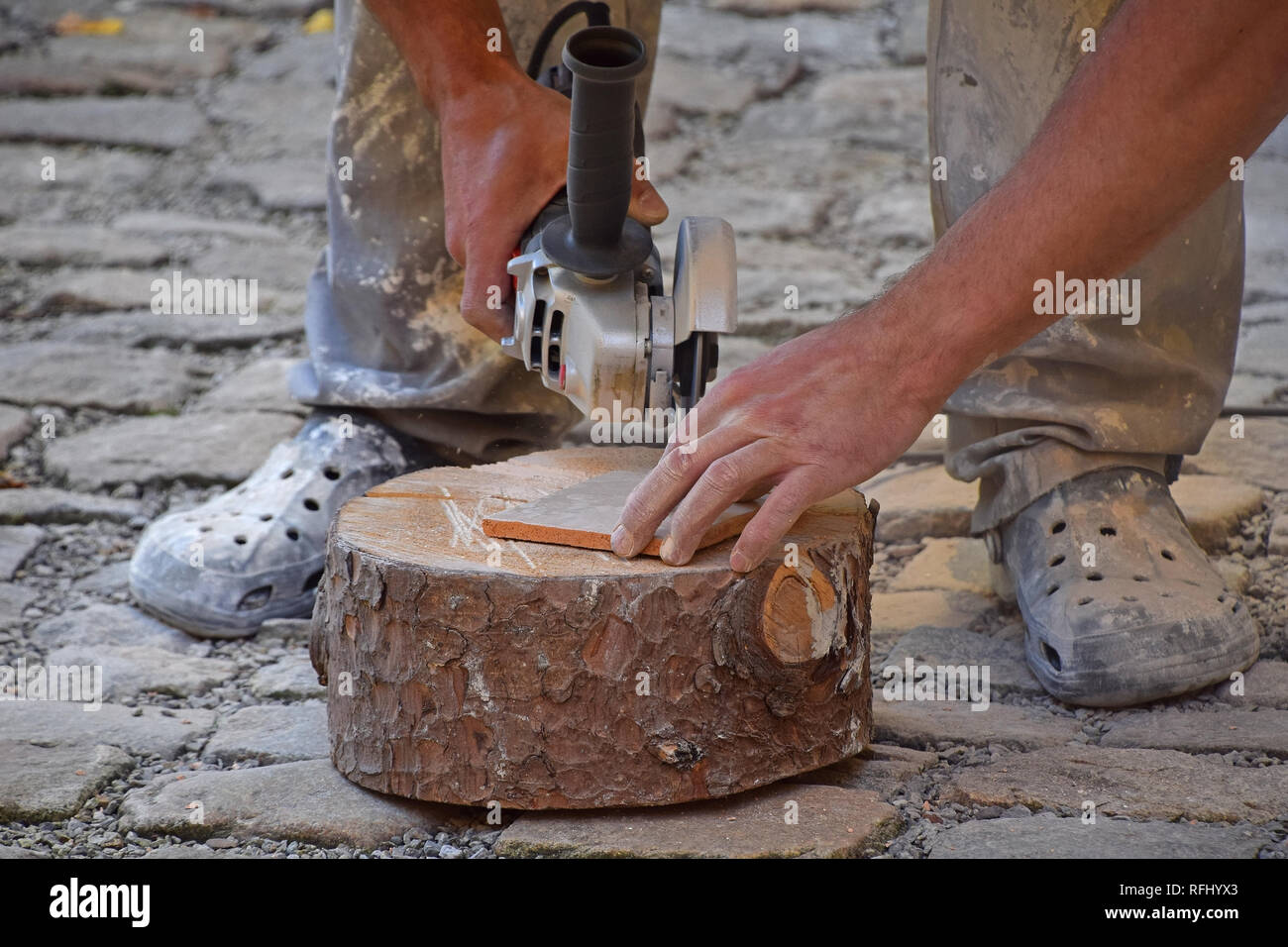 Close up of working man cutting and shaping ceramic tile with angle ...