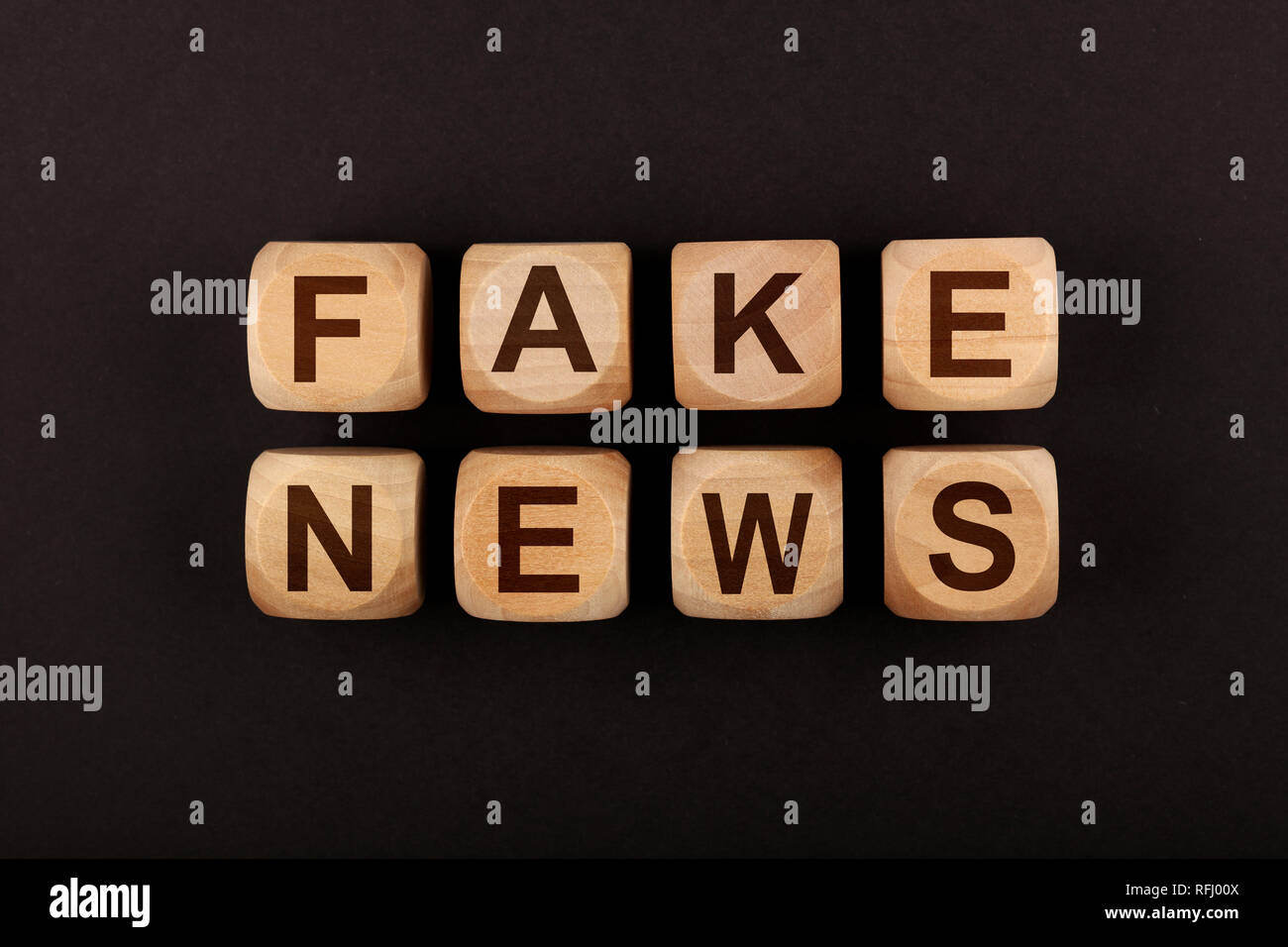 Close up wooden cube signs with FAKE NEWS words over black background ...