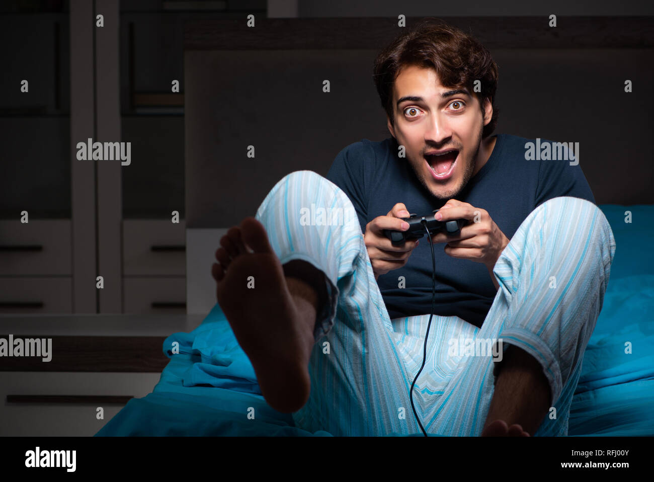 Young man playing computer games at night in bed Stock Photo - Alamy