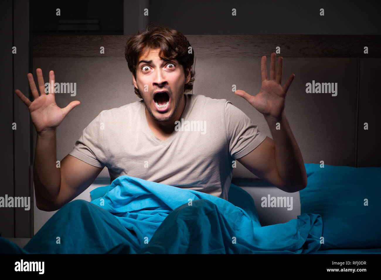 Young man scared in his bed having nightmares Stock Photo - Alamy