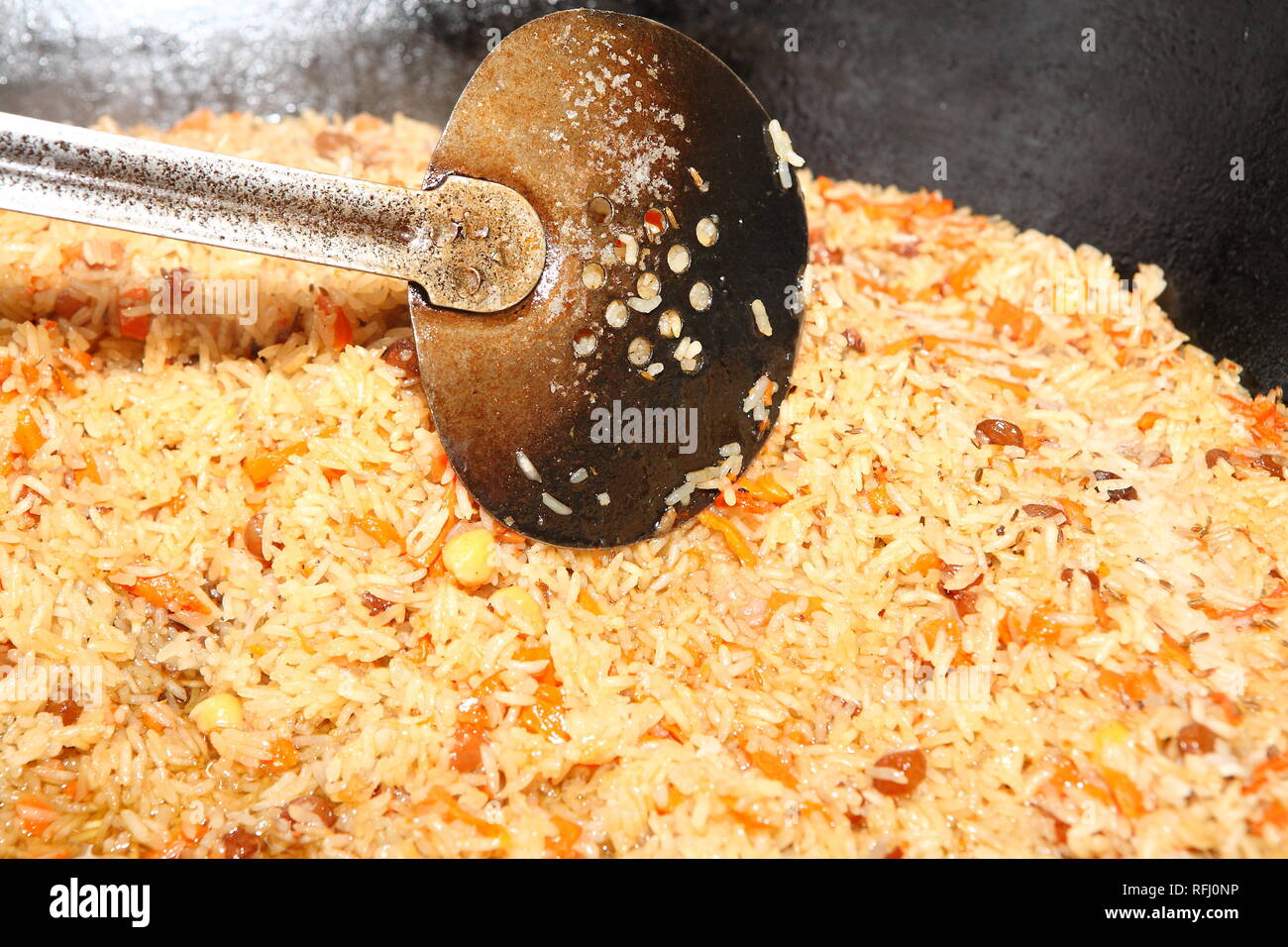 Cooking pilau in the kitchen of an oriental restaurant. Stir rice with ...