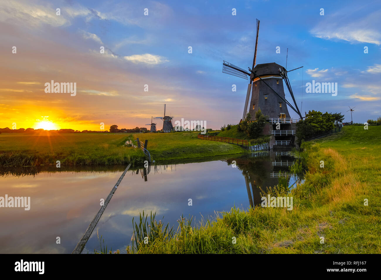 Three historic wooden windmills in a row at sunset in dutch polder ...