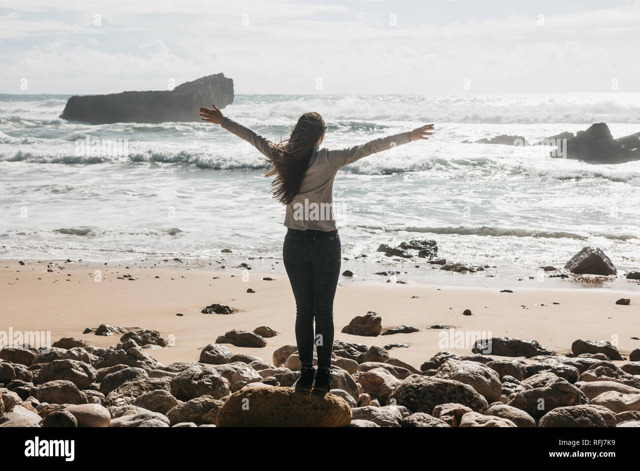 Rear view of a girl admiring the beautiful view of the Atlantic Ocean ...