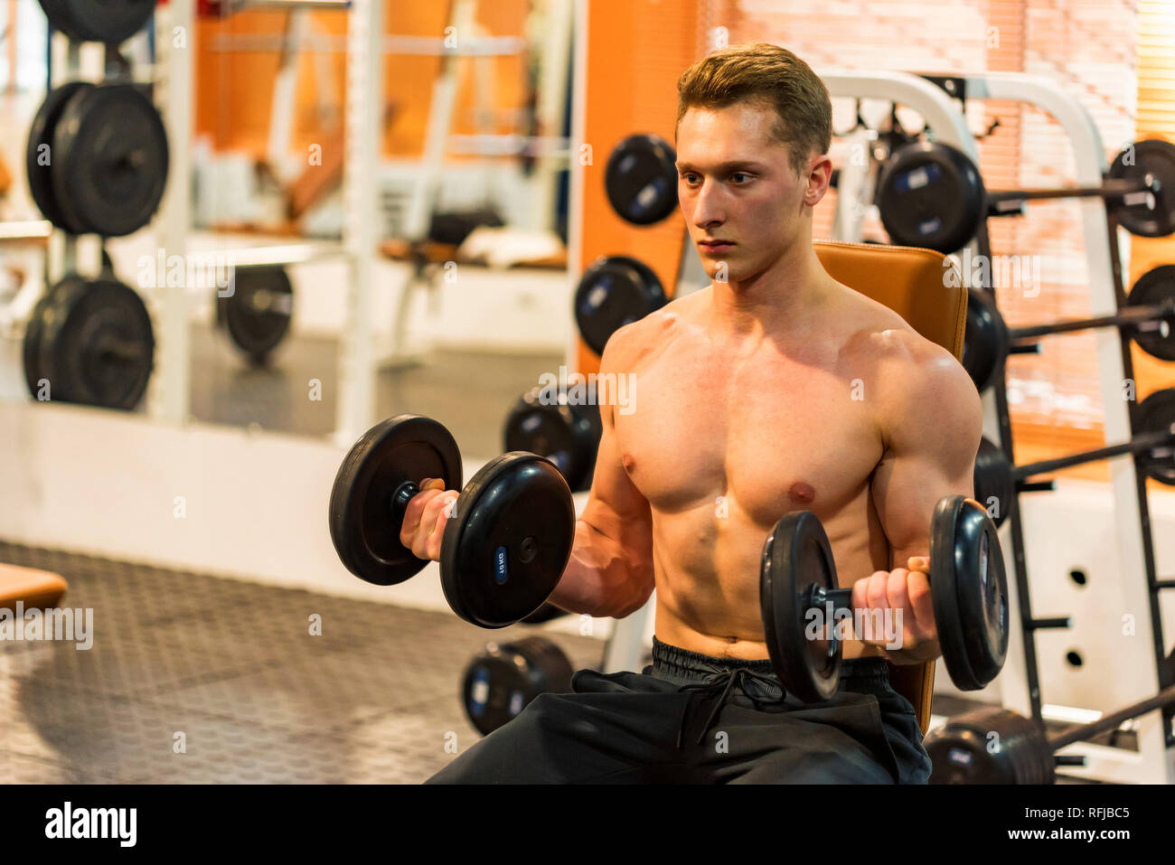 Attractive male athlete doing biceps exercise with dumbbells Stock ...