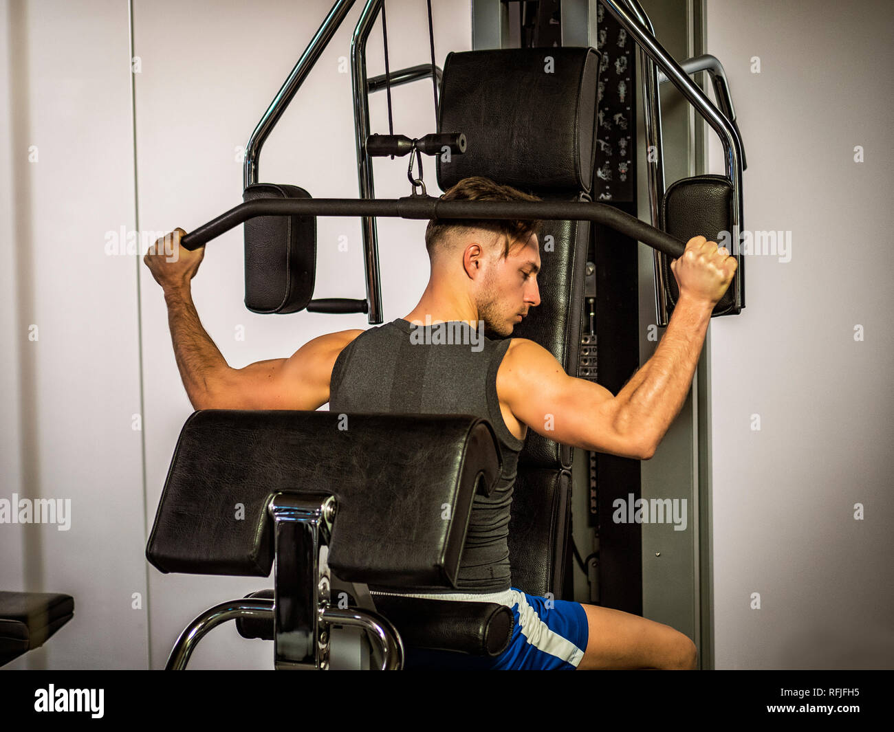 Muscular young man, training pecs on gym machine Stock Photo - Alamy