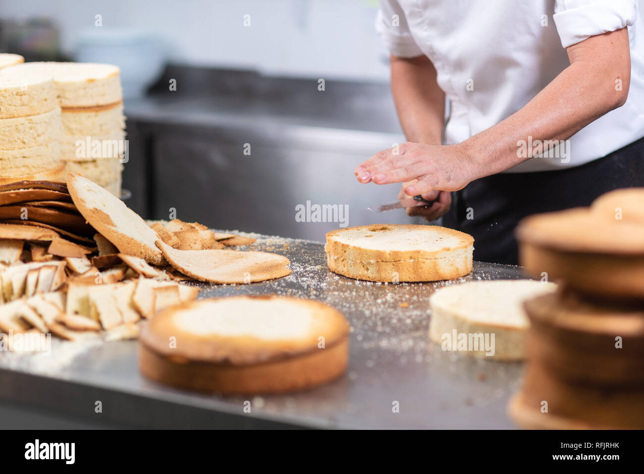 pastry chef cutting the sponge cake on layers. Cake production process ...