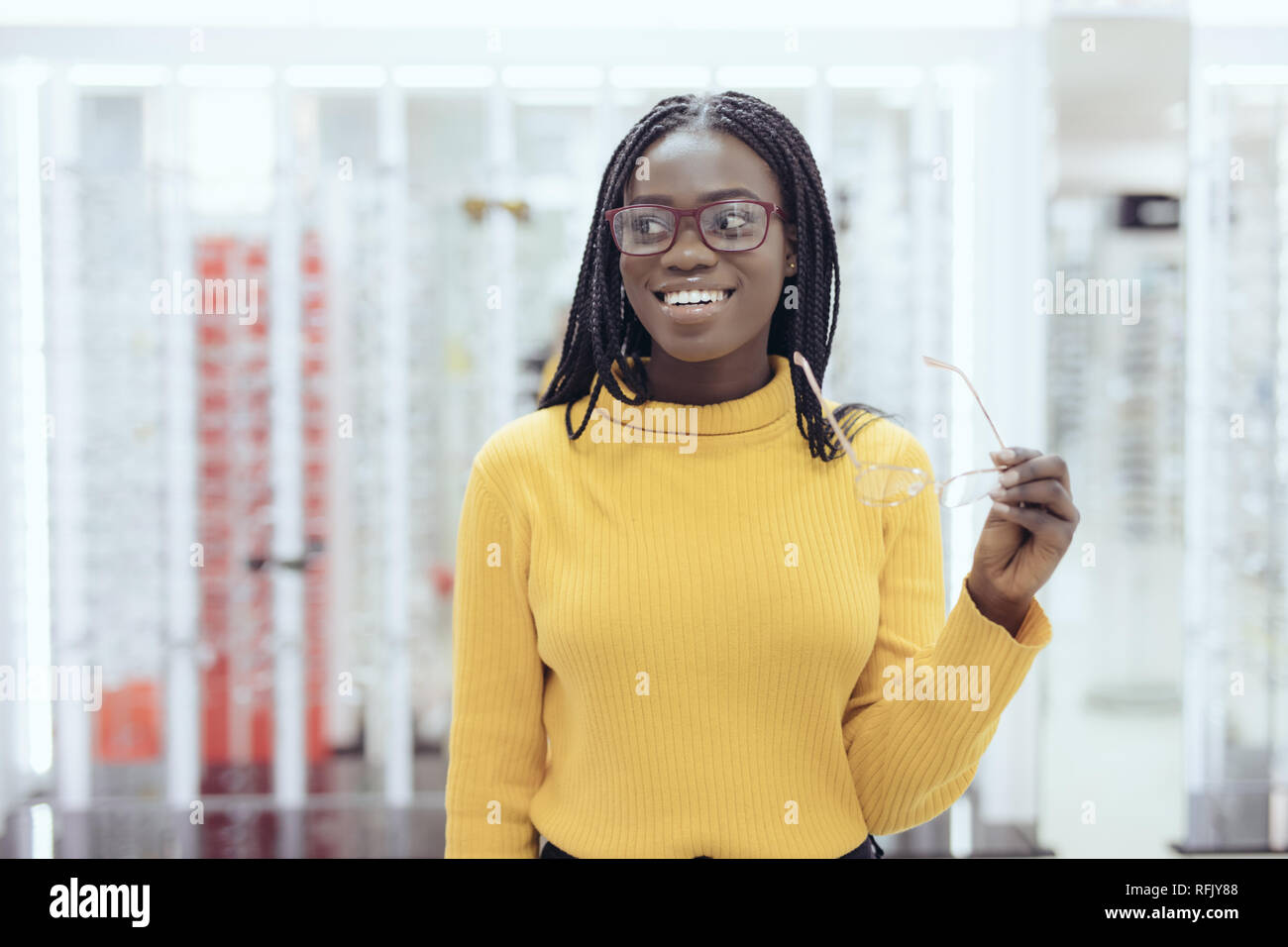 Young african woman buying eyeglasses and choosing between two frames ...