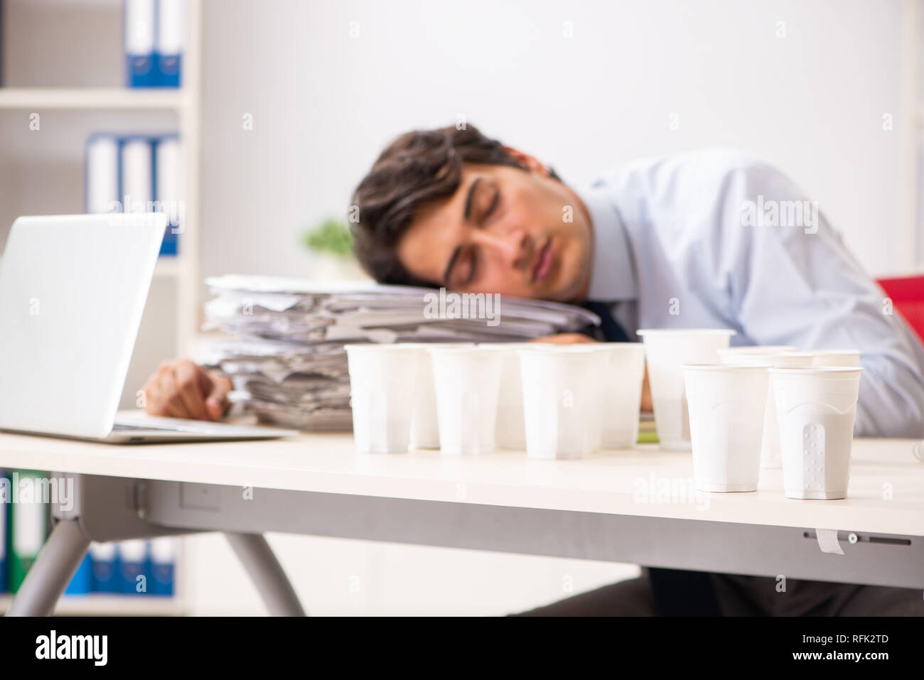 Young employee addicted to coffee Stock Photo - Alamy