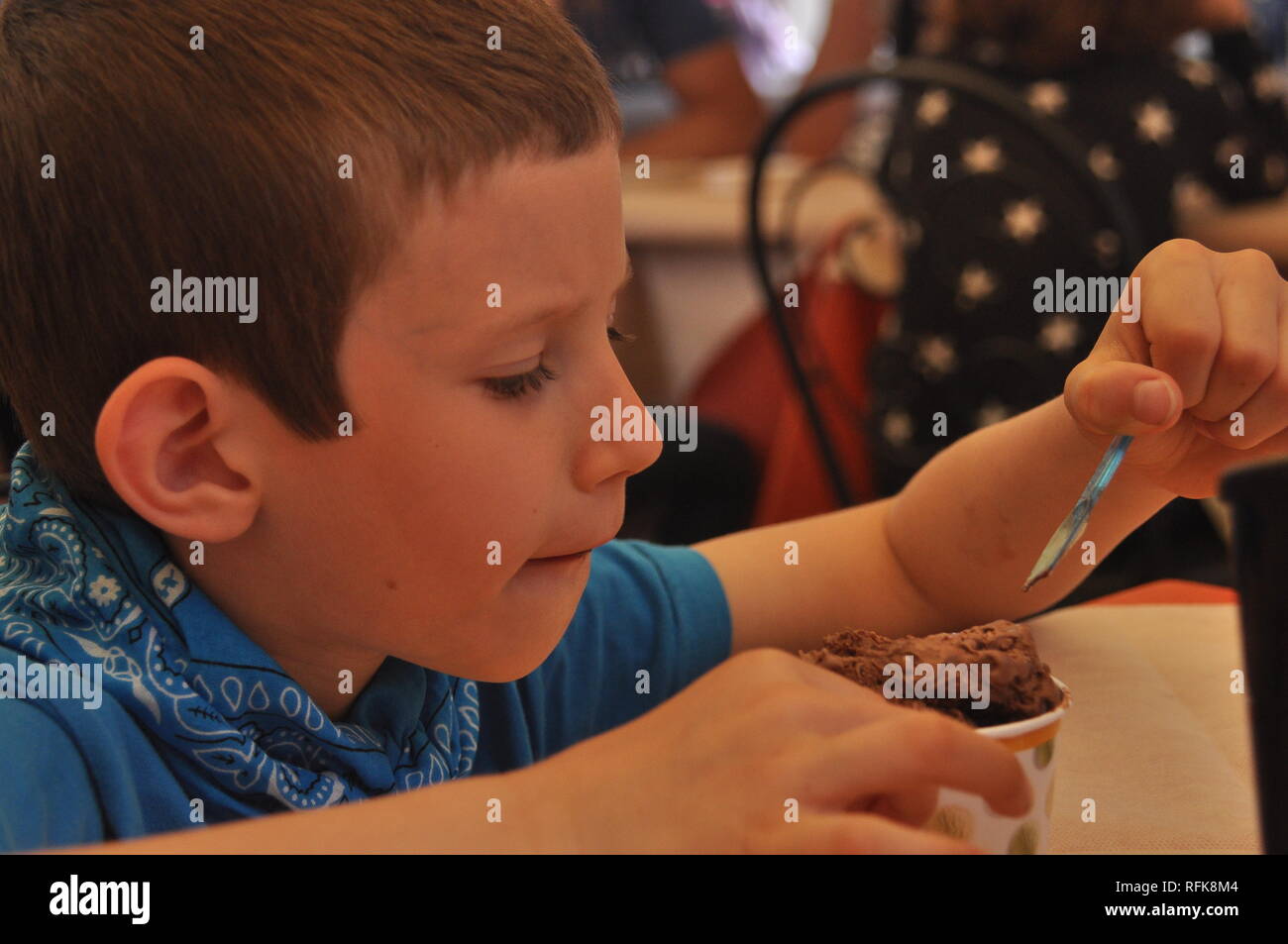 A boy in a blue shirt eating chocolate ice cream in a restaurant Stock ...
