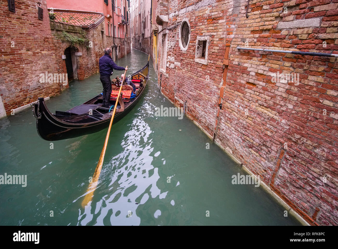 A Gondola, the traditional venetian rowing boat, is cruising on a small ...