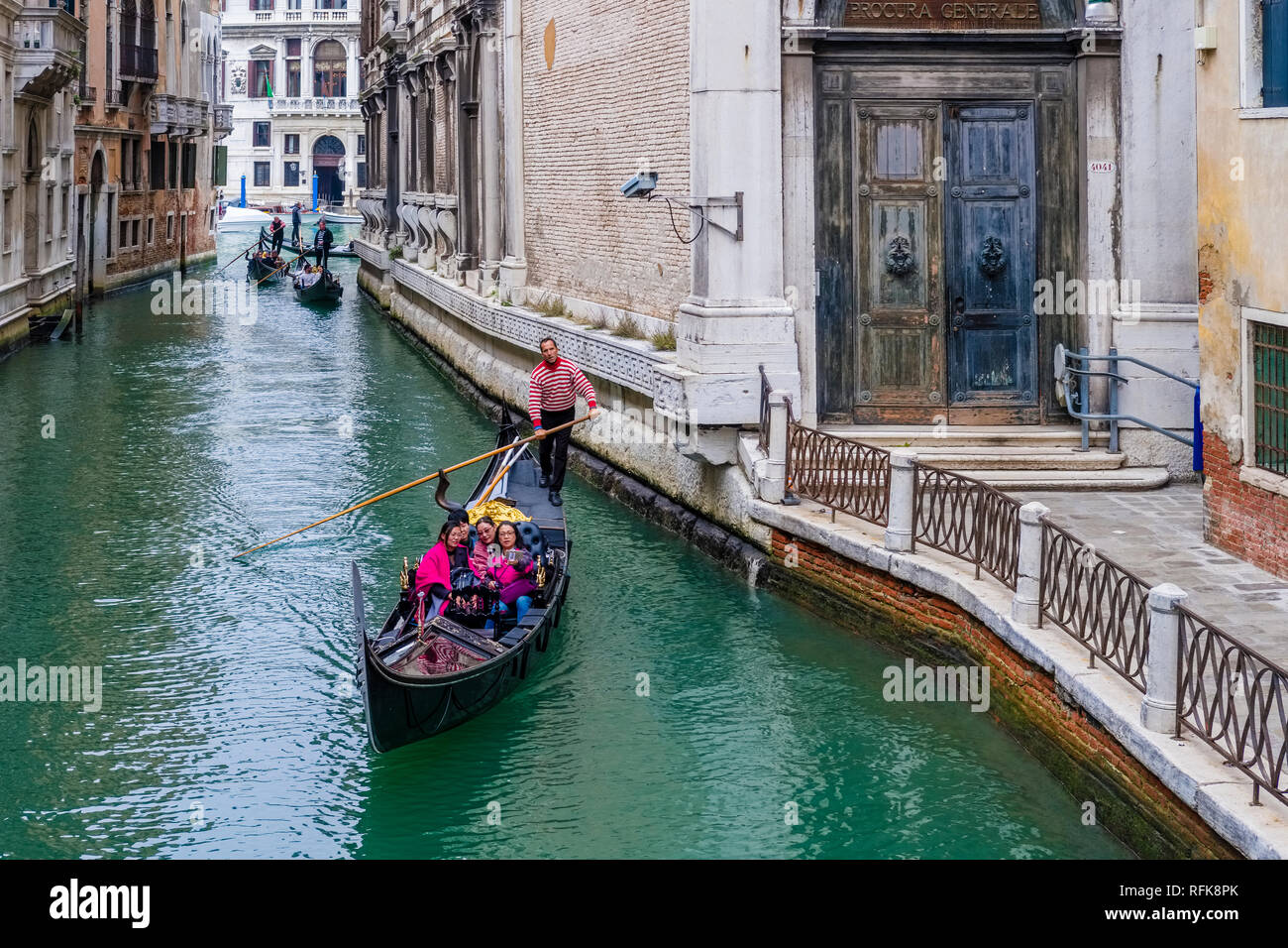 A Gondola, the traditional venetian rowing boat, is cruising on a small ...