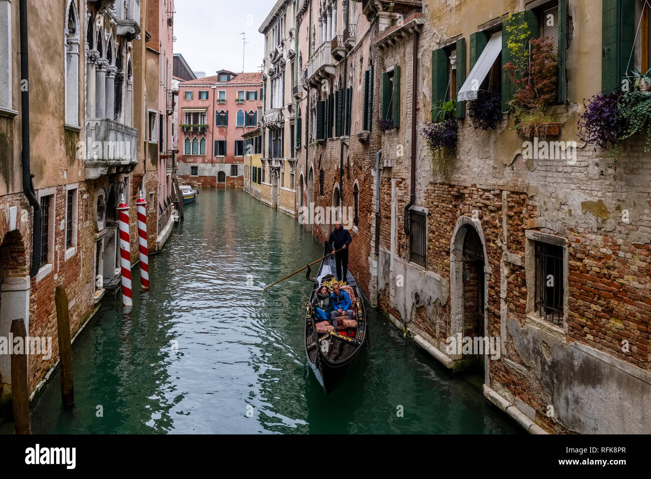 A Gondola, the traditional venetian rowing boat, is cruising on a small ...