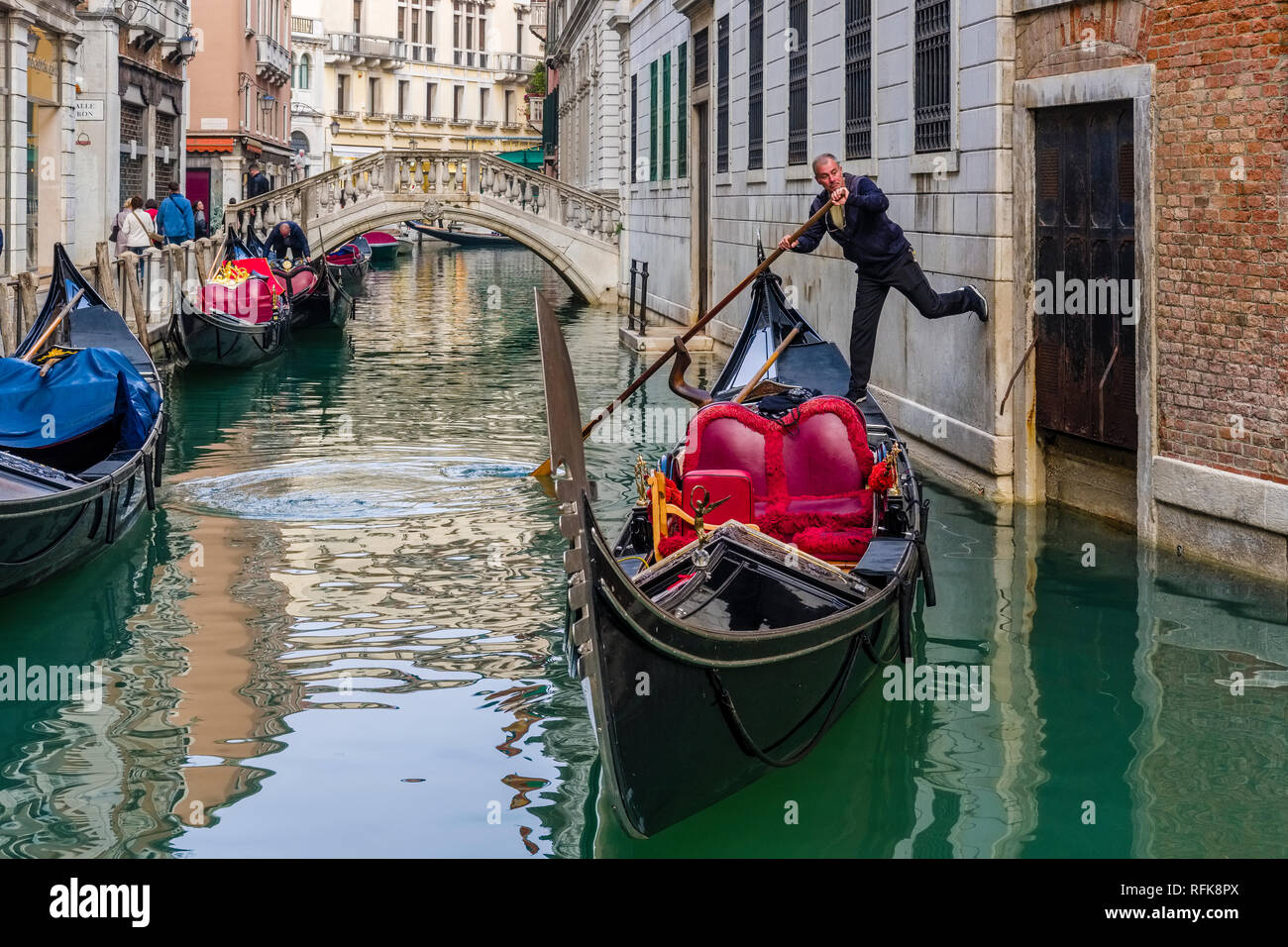 A Gondola, the traditional venetian rowing boat, is cruising on a small ...