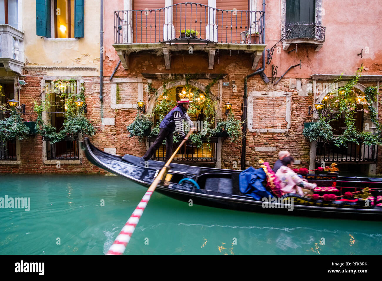 A Gondola, the traditional venetian rowing boat, is cruising on a small ...