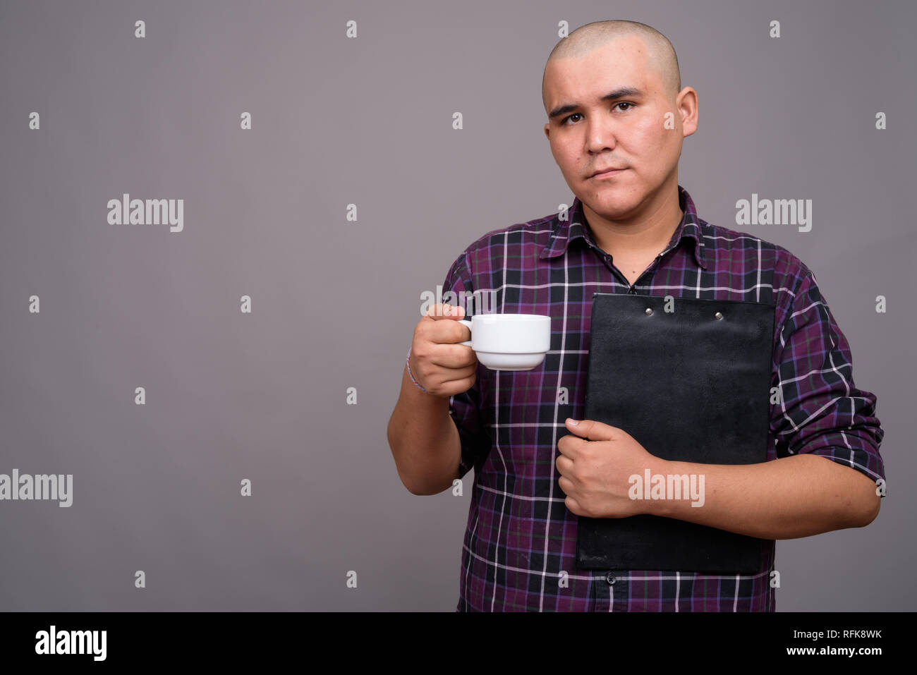 Young bald Asian businessman against gray background Stock Photo - Alamy