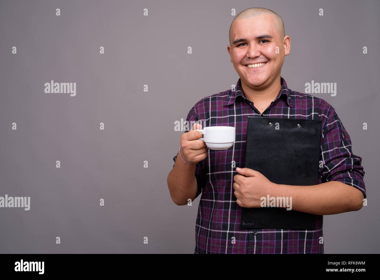 Young bald Asian businessman against gray background Stock Photo - Alamy