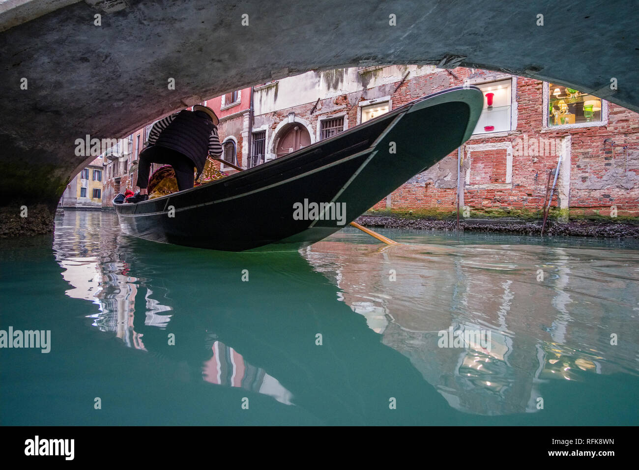 A Gondola, the traditional venetian rowing boat, is cruising on a small ...