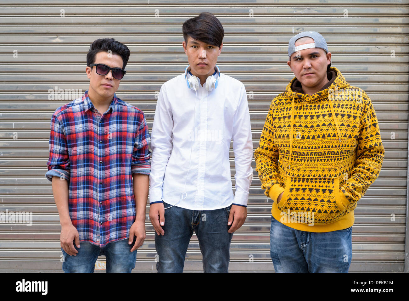 Three young Asian men standing against warehouse door in the str Stock ...