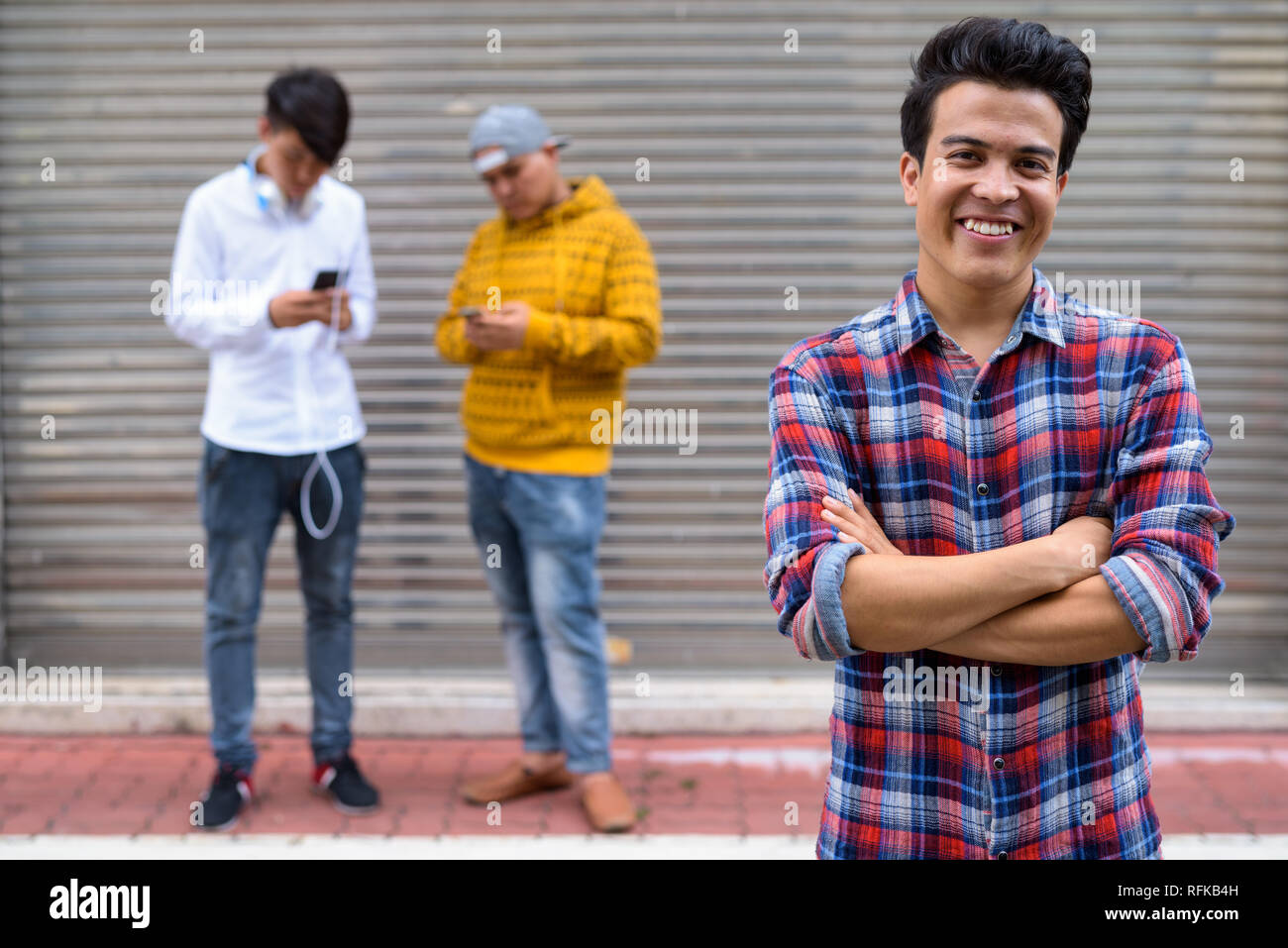 Three young Asian men standing against warehouse door in the str Stock ...