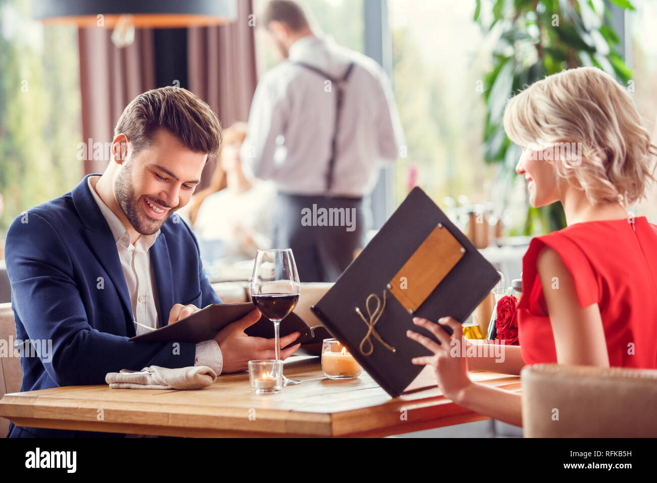 Young couple on date in restaurant sitting choosing dish from menu ...