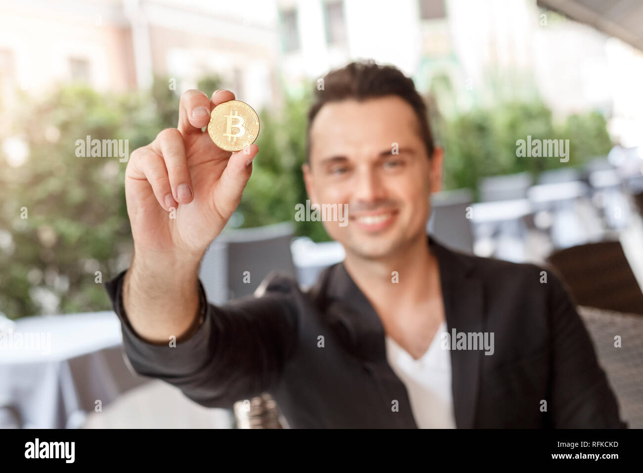 Lunch time. Young man in suit sitting at cafe on city street with ...