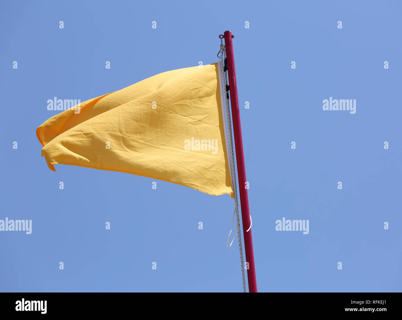 big yellow flag waving in the blue sky as a warning Stock Photo - Alamy