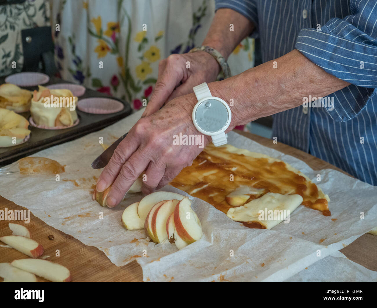 Hands of old woman are slicing an apple to baking a cake. Close up ...