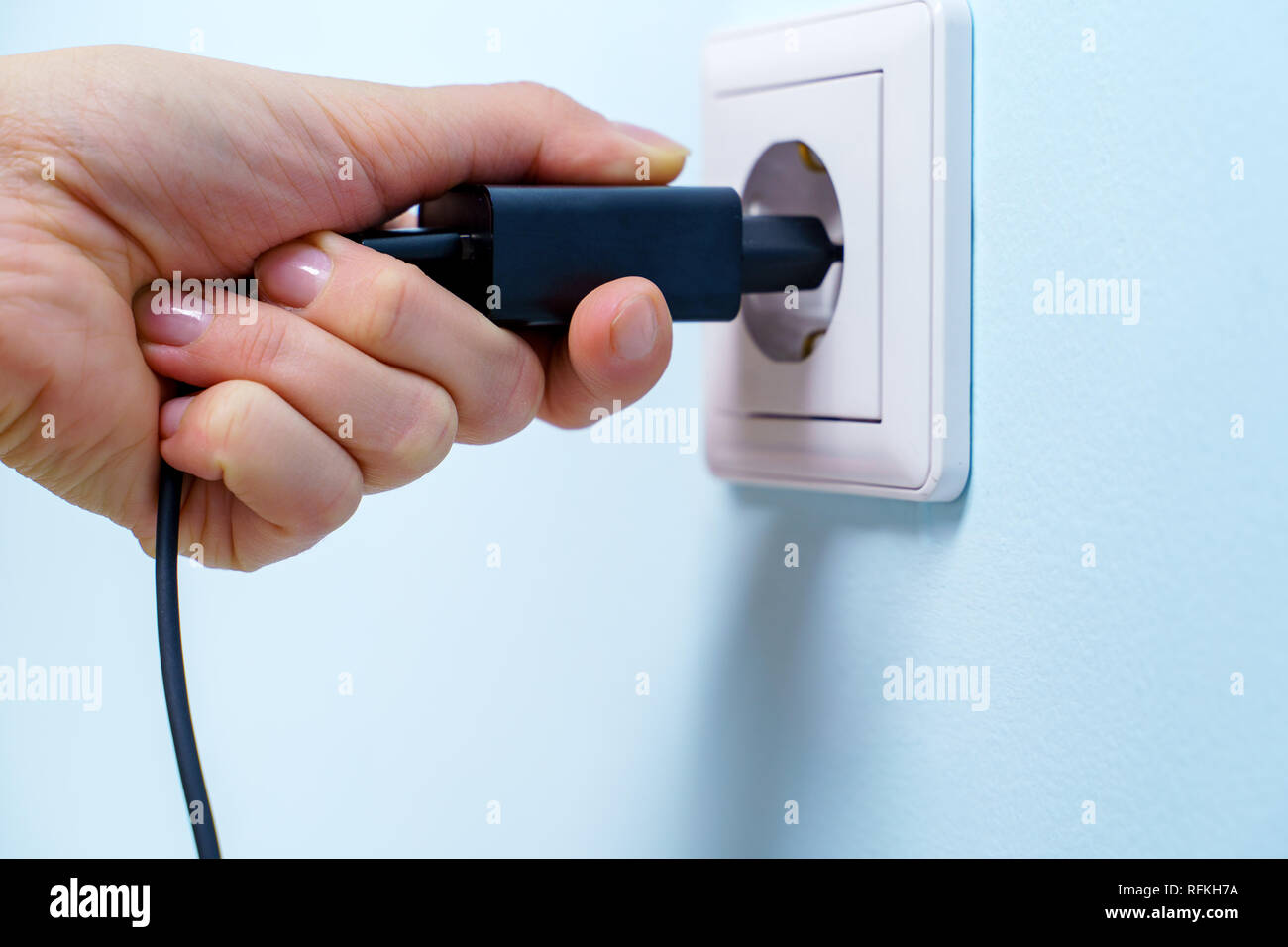 Image of hand with charger in socket Stock Photo - Alamy