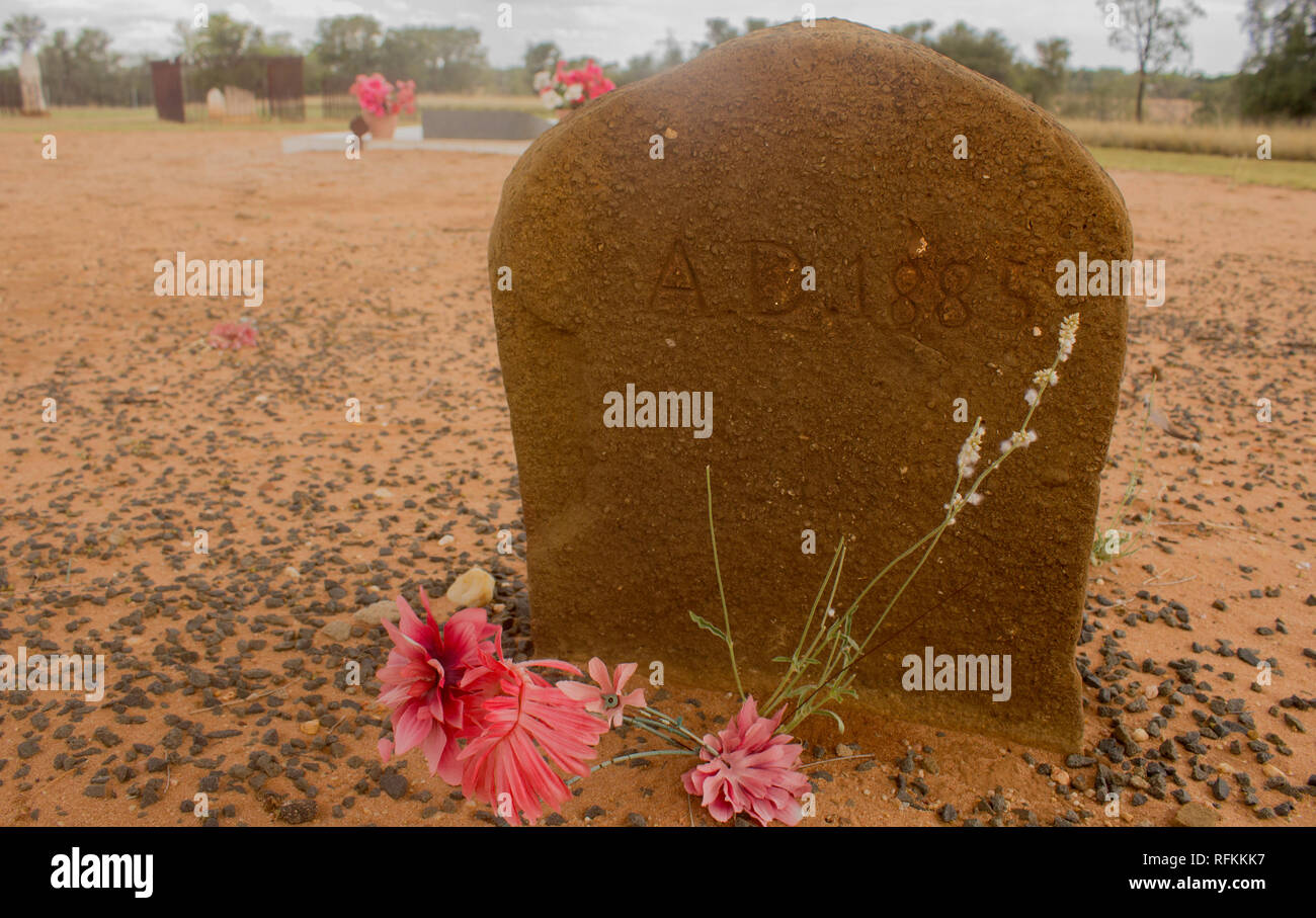 An unmarked gravestone with the date AD 1895 in a dirt cemetery, with ...