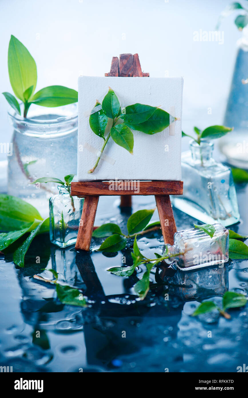 Artistic easel with a green leaf and glass jars with fresh plants ...