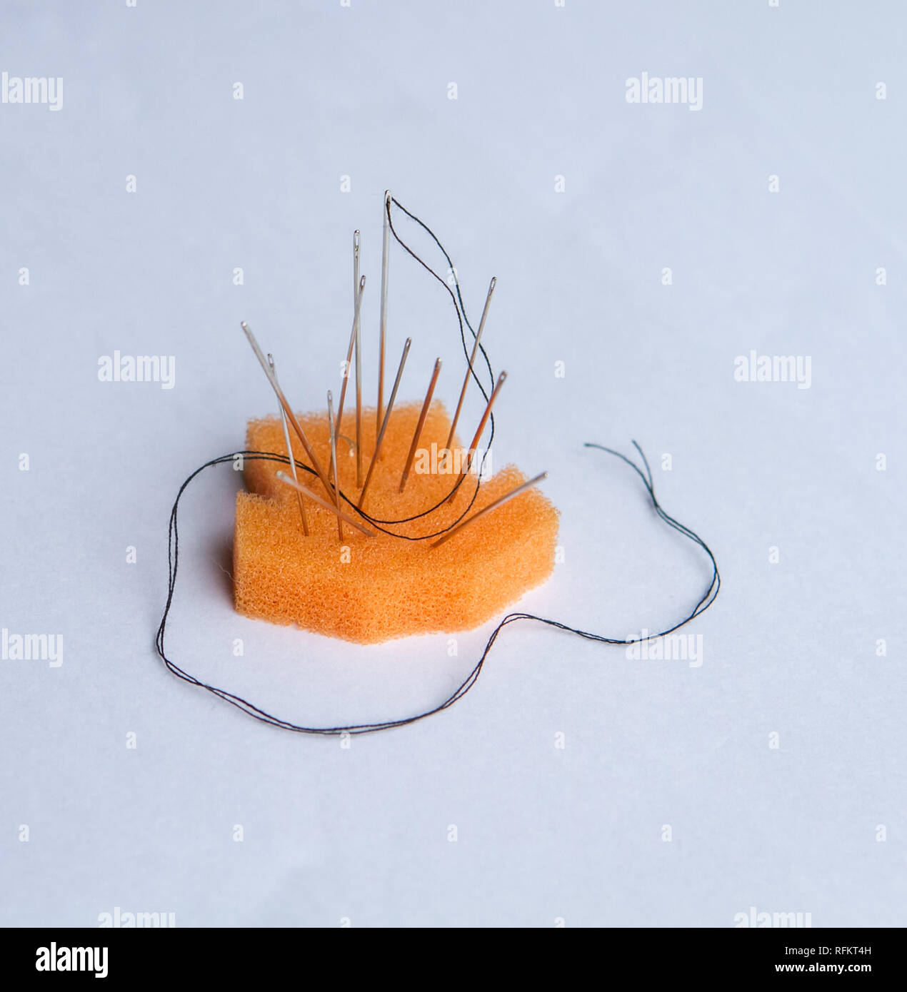 Needles for sewing on orange sponge Stock Photo - Alamy