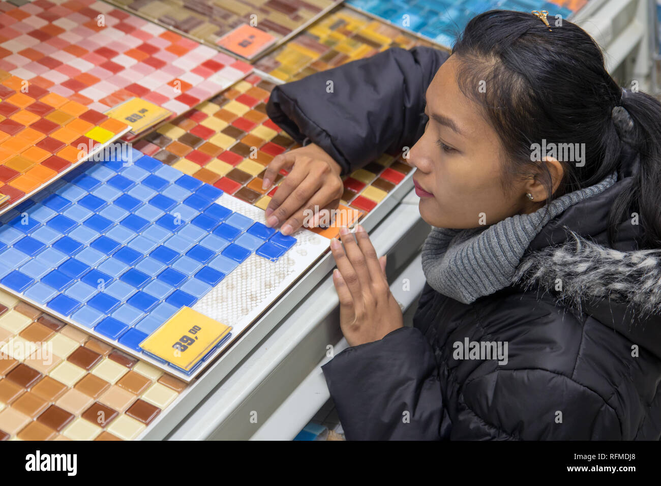 A young woman chooses tiles in a shop.Purchase of colored tiles in a ...