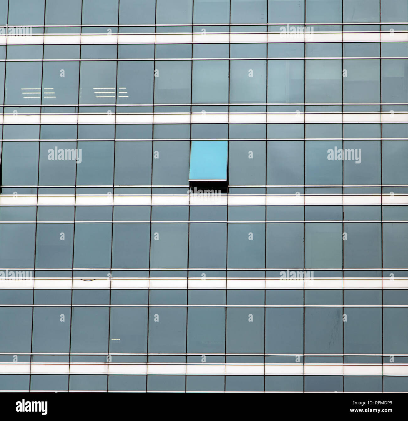 The glass facade of skyscraper with many identical windows and only one ...