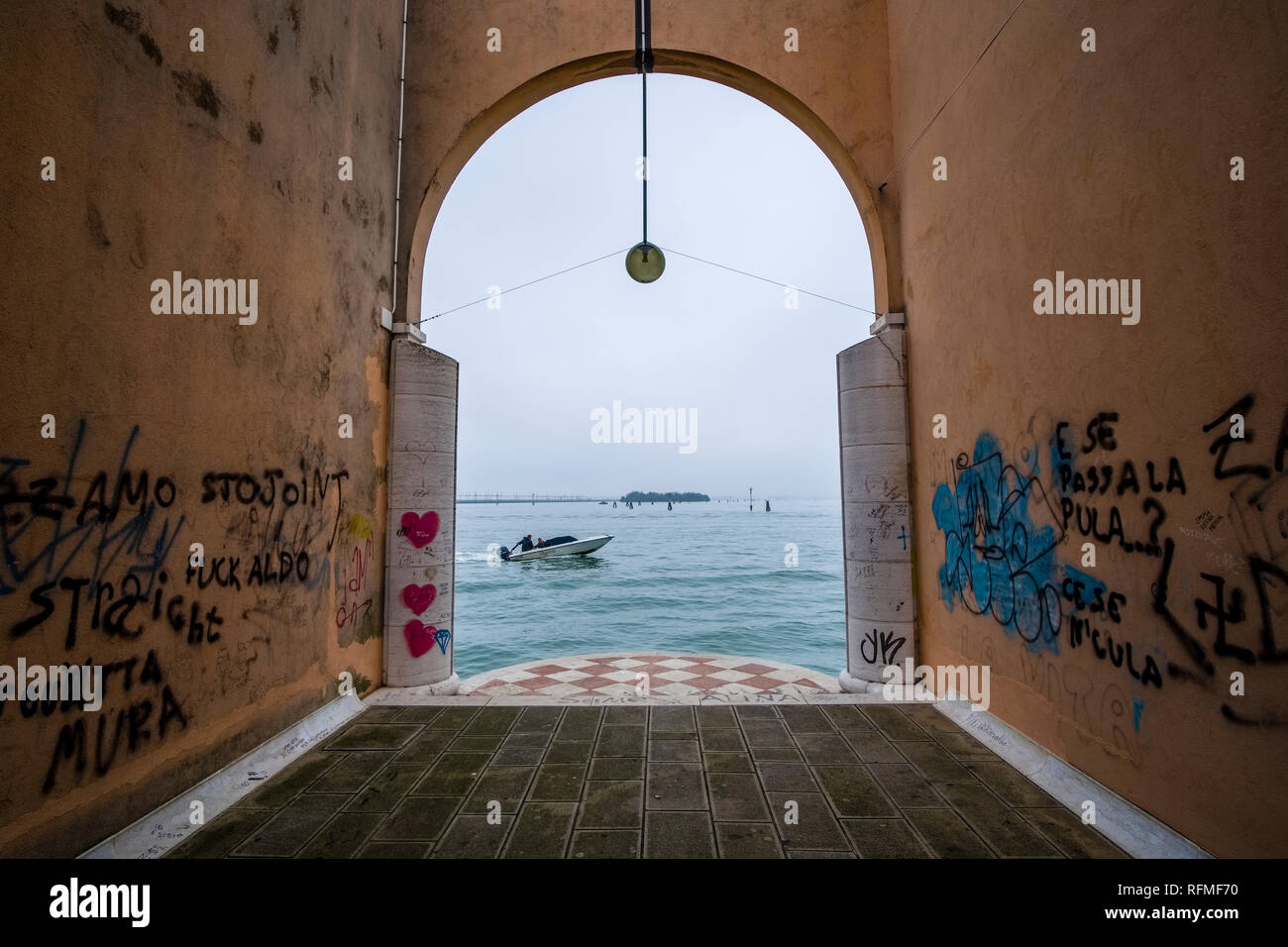 A gate, sprayed with colorful graffity, is leading out to the waters of ...