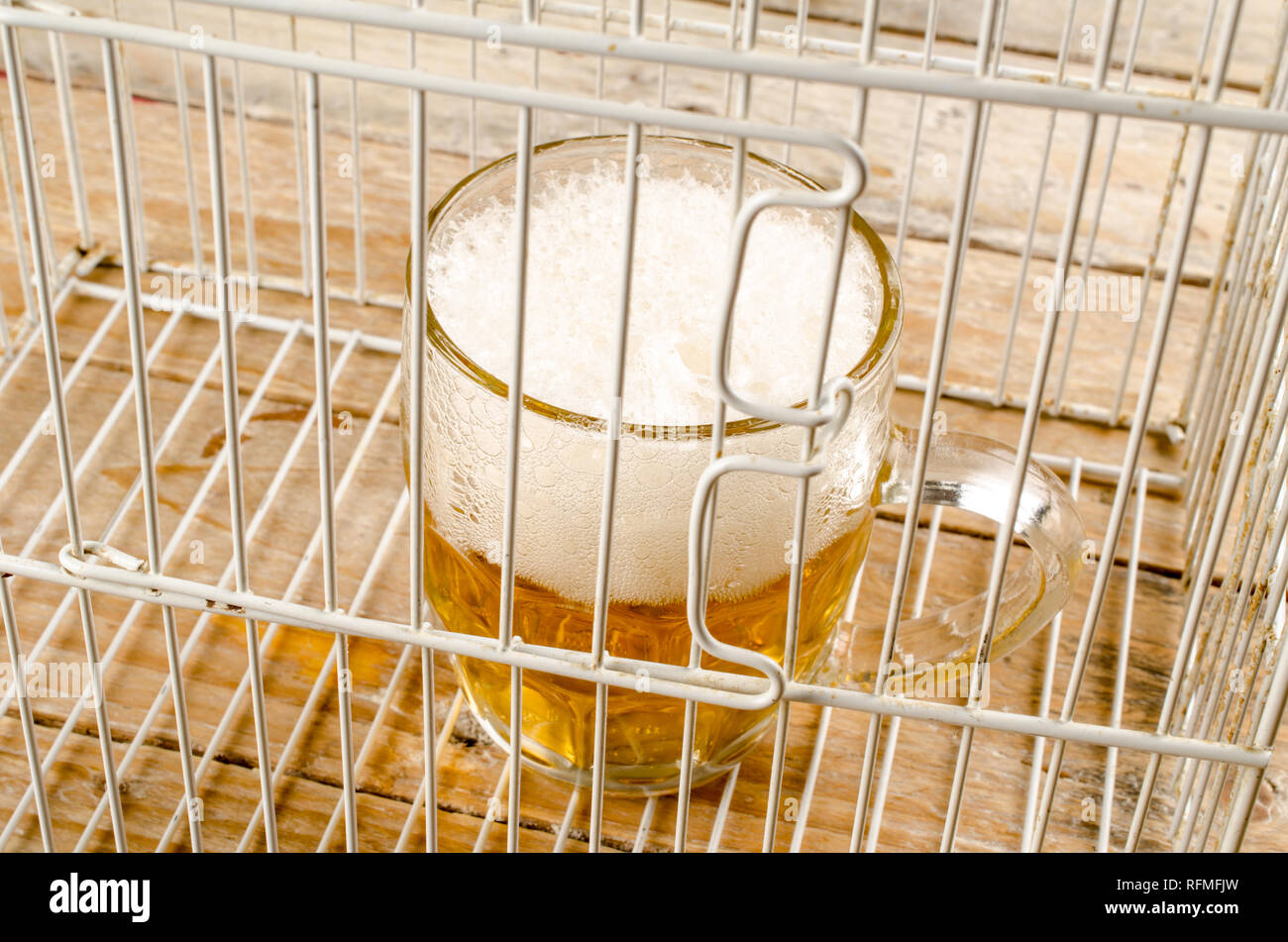 Glass of beer inside a cage, a concept on alcohol addiction and abuse ...