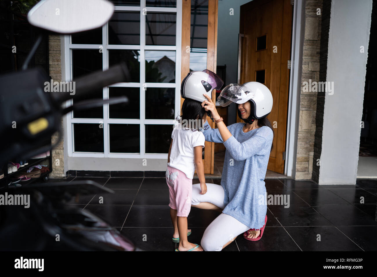 mom helped her daughter to put on helmet Stock Photo - Alamy