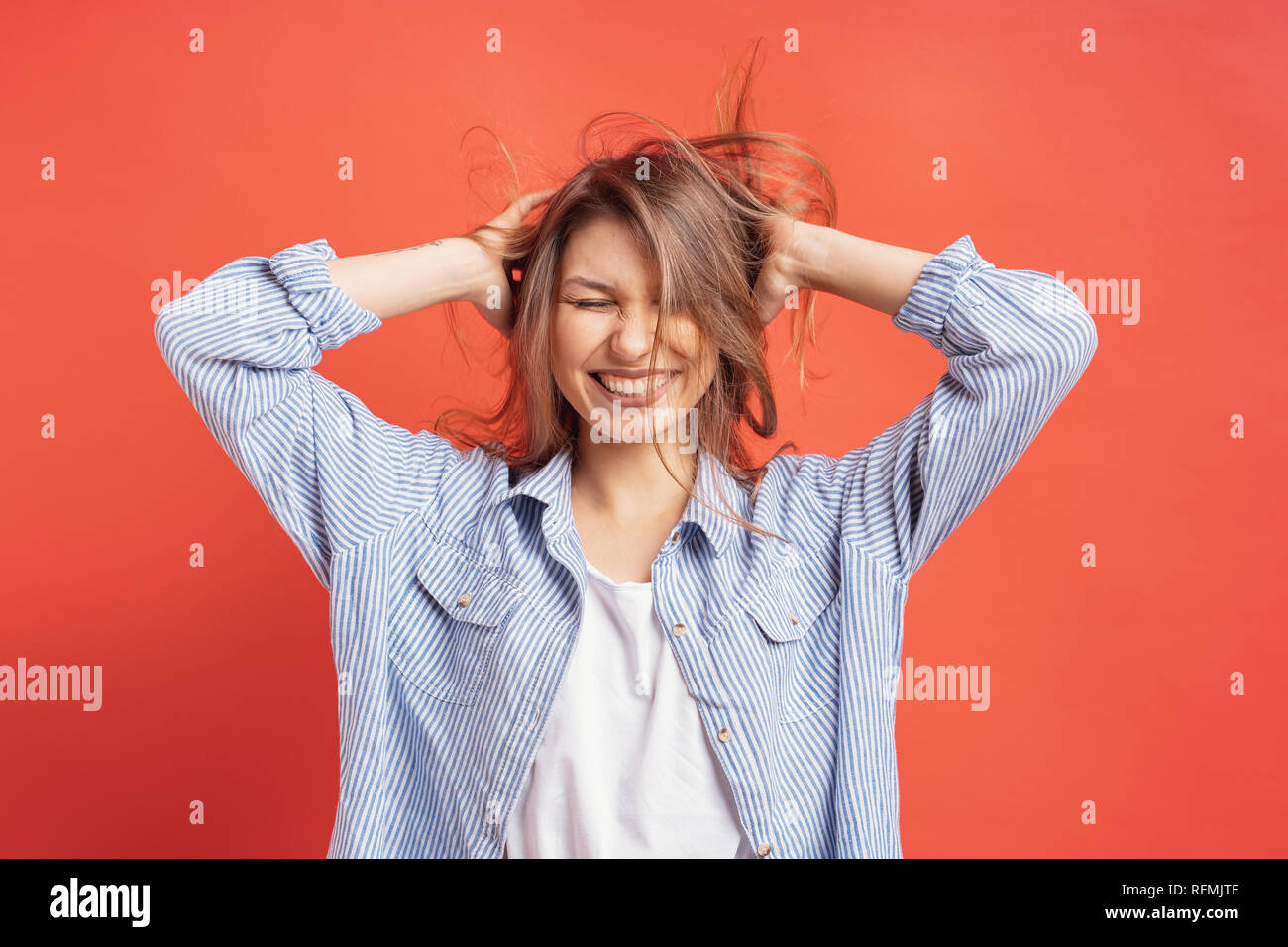 Funny, cute girl having fun isolated on a red background while playing ...