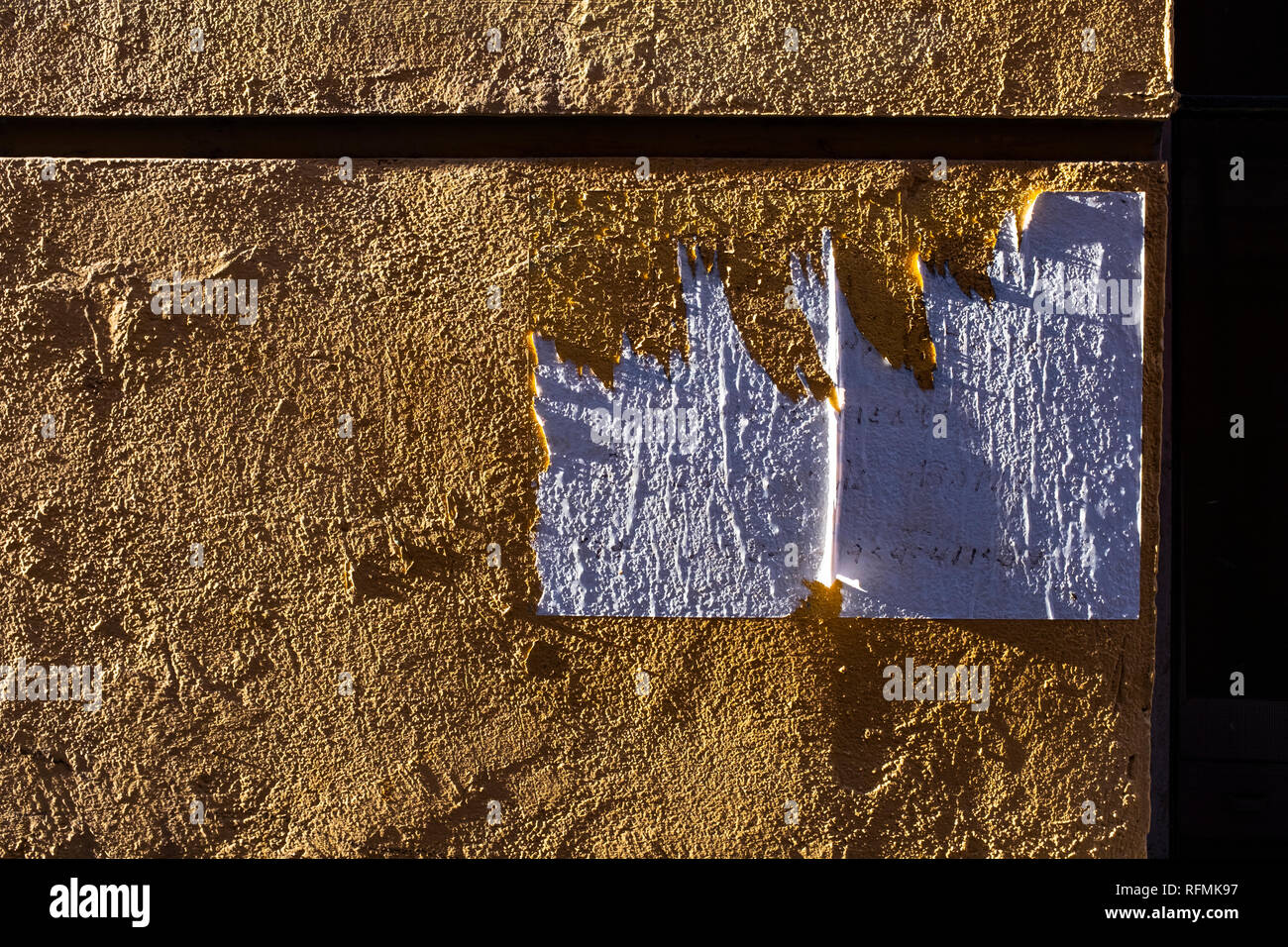 Rough textured painted wall with strong shadows cast by direct sunlight ...