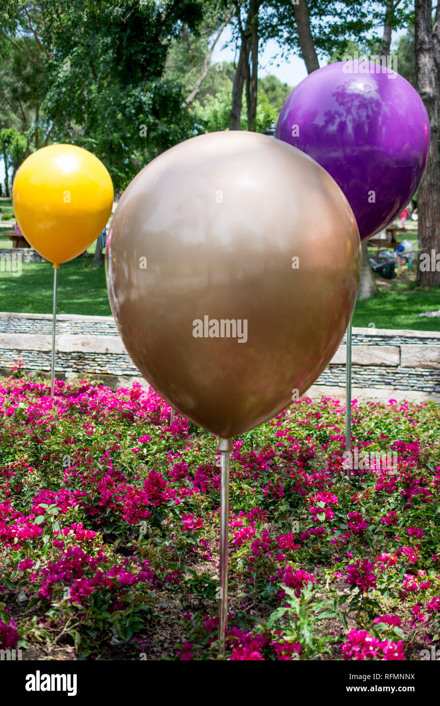 Color baloons are placed in a park by the flowers Stock Photo - Alamy