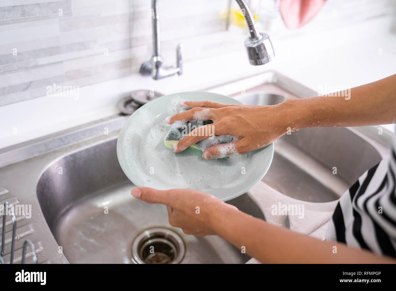 female hand gesture cleaning plate using sponge Stock Photo - Alamy