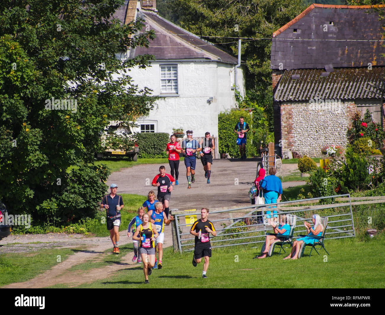 Runners running through a farm yard during a trail running race Stock ...