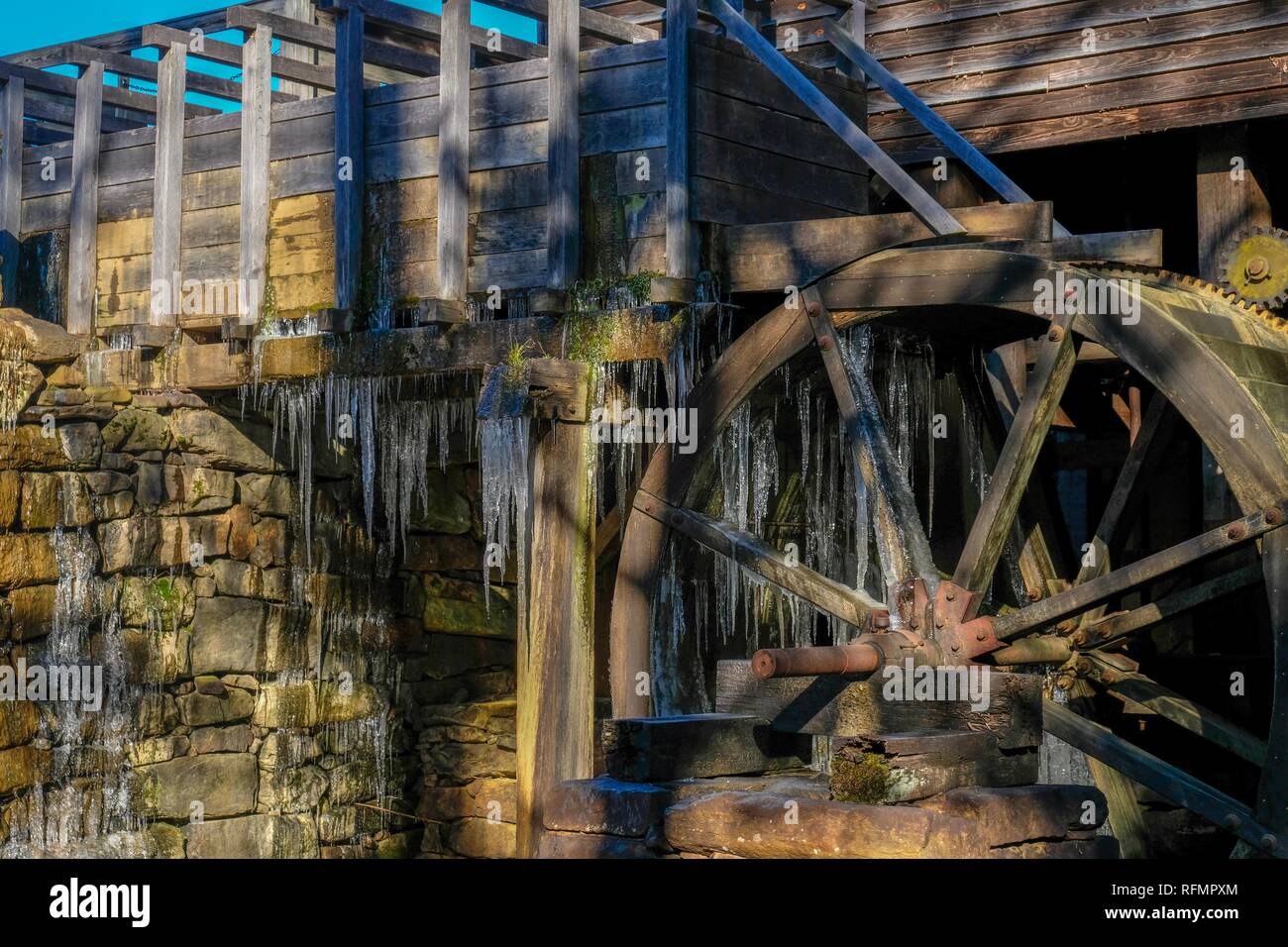 Long icicles hang from the flume and waterwheel of the old gristmill at ...