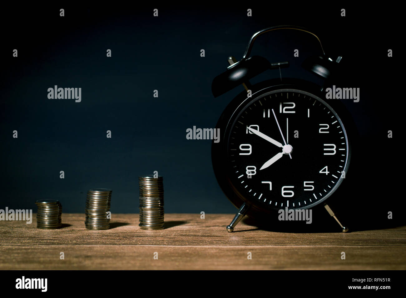 Black alarm clock with money Stock Photo - Alamy