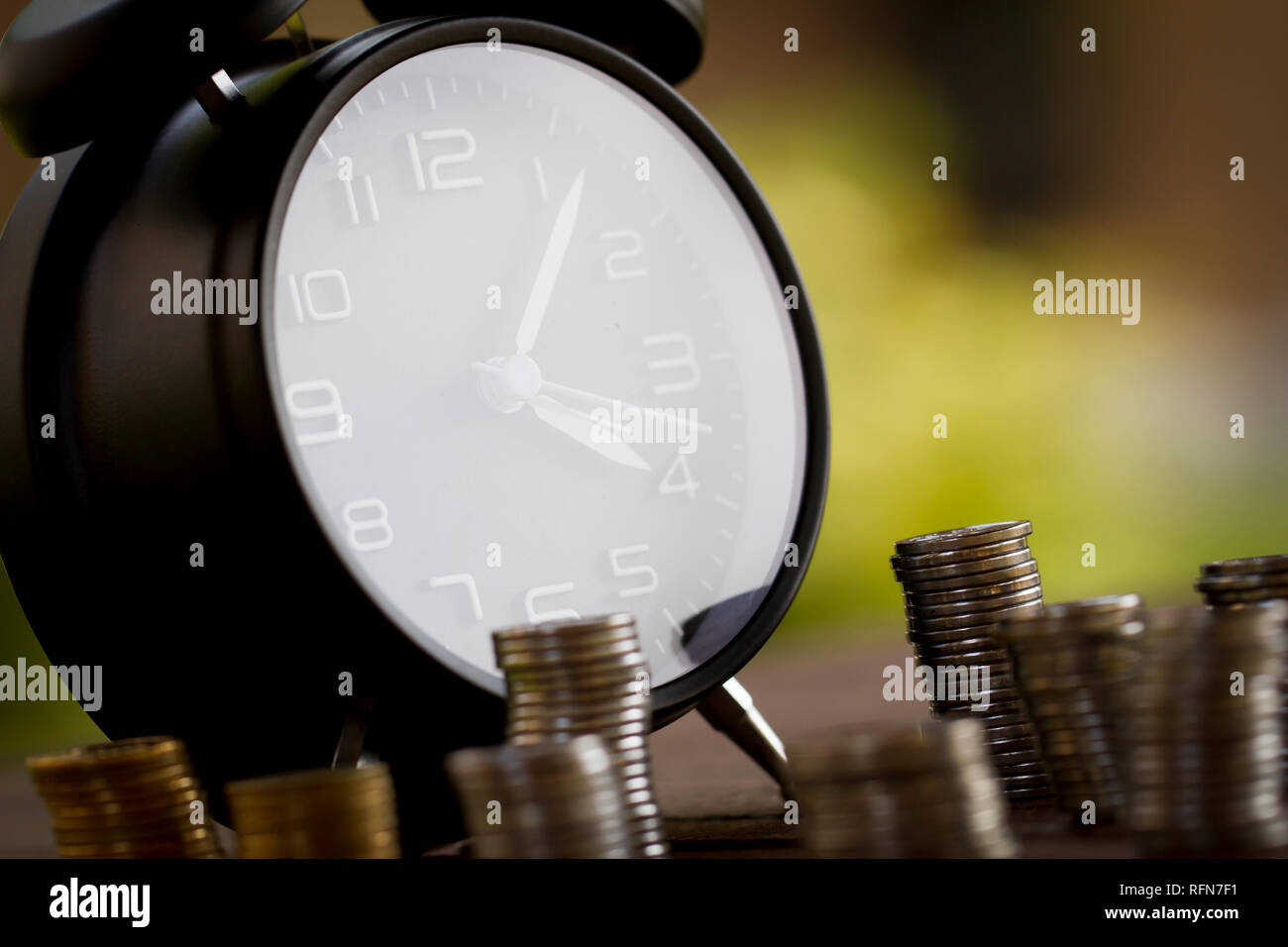 Black alarm clock with money Stock Photo - Alamy