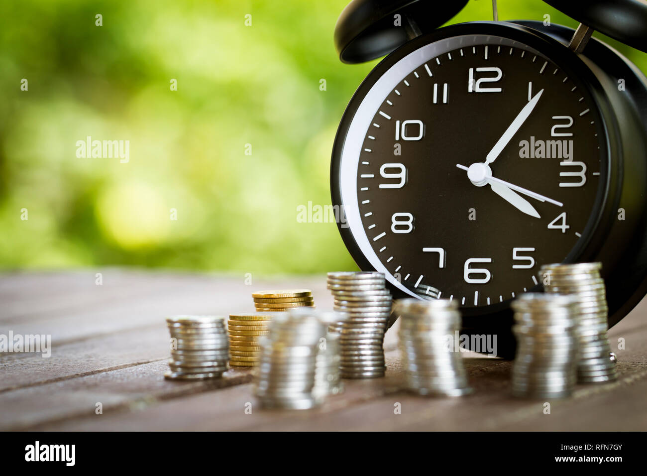 Black alarm clock with money Stock Photo - Alamy